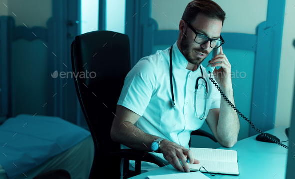 Mid adult doctor making a phone call at doctor's office. Stock Photo by ...