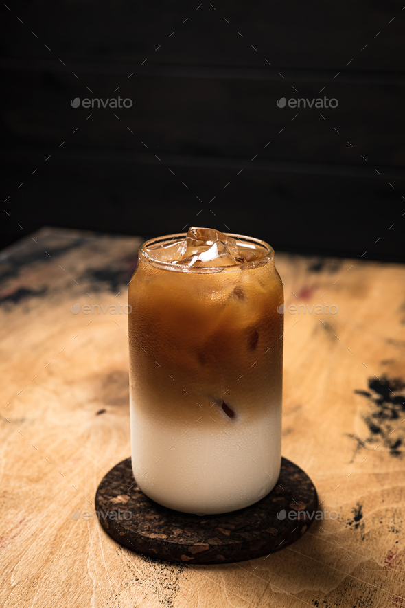 Cold iced latte coffee. A tall highball glass filled with ice cubes, layered refreshing drink ...