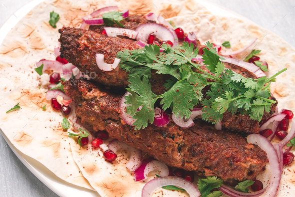 Lula kebab, on lavash, with red onion, pomegranate, and sumac, top view ...