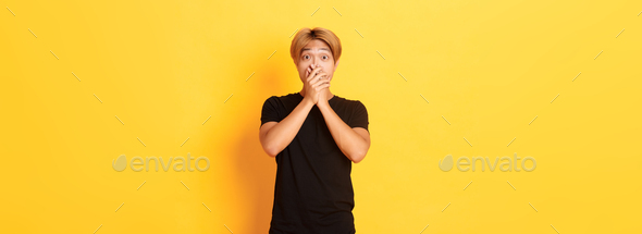 Portrait of surprised gasping asian guy with blond haircut, cover mouth ...