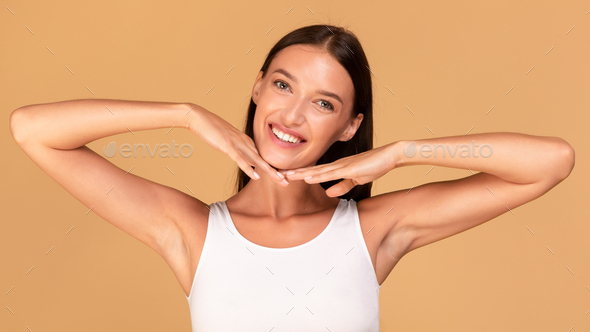 Beauty care. Happy beautiful woman touching chin with hands, attractive ...