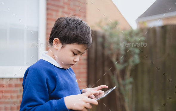 kid holding tablet pc waiting for School bus, boy learning with modern ...
