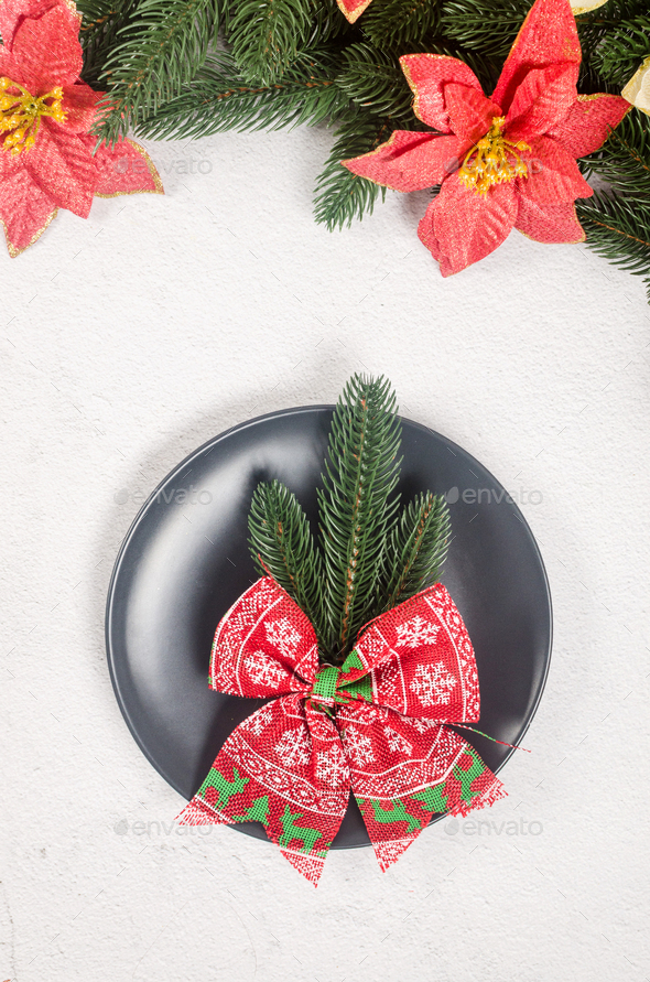 Christmas table setting with empty black plate and red decorations ...