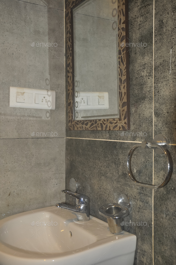 Ceramic wash basin and mirror on the tiled wall inside modern bathroom ...