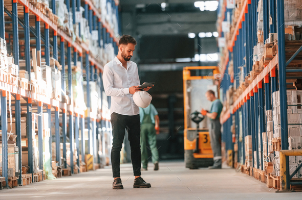 Using tablet to check the products. Storage worker is in the warehouse ...