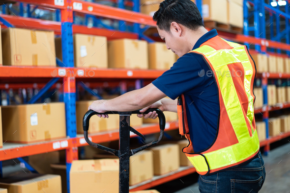 Asian male worker pushing trolley with boxes to the shelves at the ...