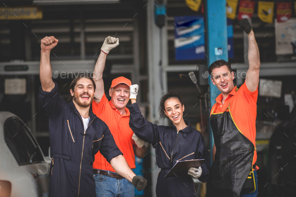 Group of young and senior car mechanics in garage wearing uniform ...