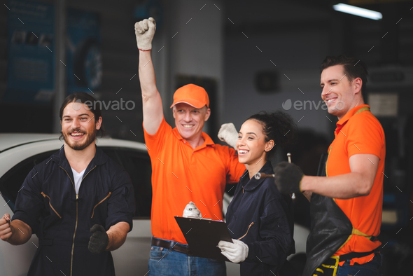 Group of young and senior car mechanics in garage wearing uniform ...