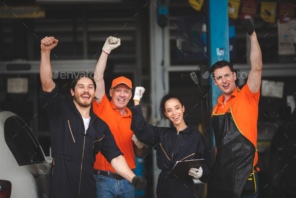 Group of young and senior car mechanics in garage wearing uniform ...