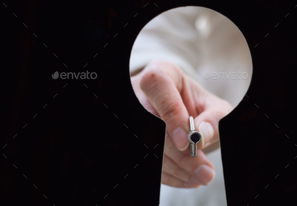 Person's hand with a key through a keyhole Stock Photo by JulieAlexK