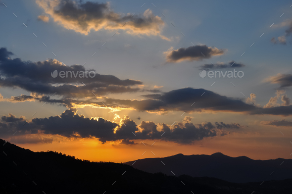 High resolution shot of sun behind clouds during sunset of hilly area ...