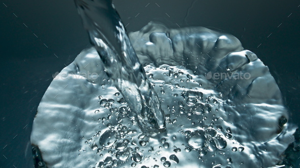 Mineral water pouring transparent glass closeup. Blebs going up smooth ...