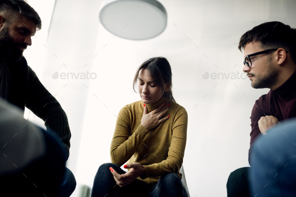 Depressed woman sharing her problems with members of group therapy ...