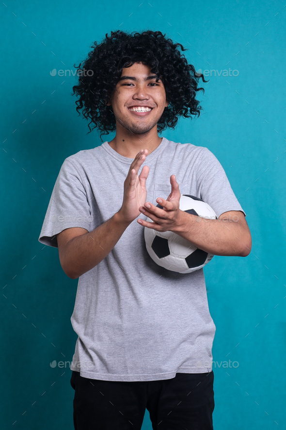 Young man clapping hands while holding soccer ball Stock Photo by ...