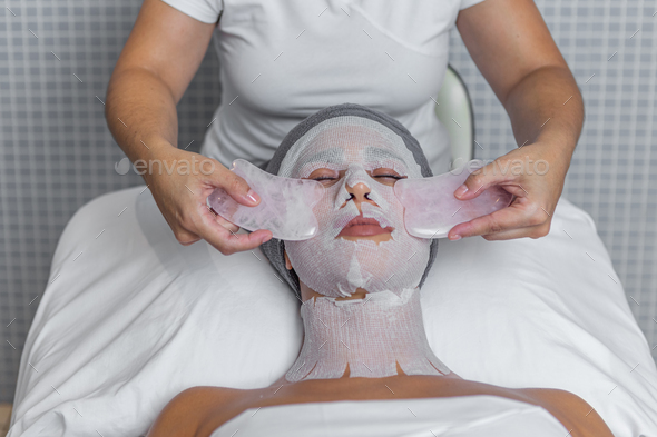 Close up of woman in spa receiving gua sha facial massage treatment by ...