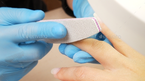 Manicurist files the shape of the nails with a special nail file, close ...