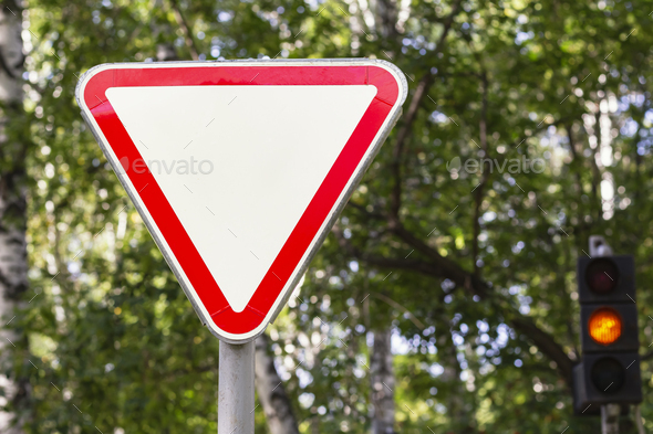 Triangular traffic sign Give way outside an green foliage in blur ...