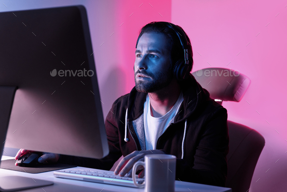 Concentrated young man looking at the computer monitor while sitting ...