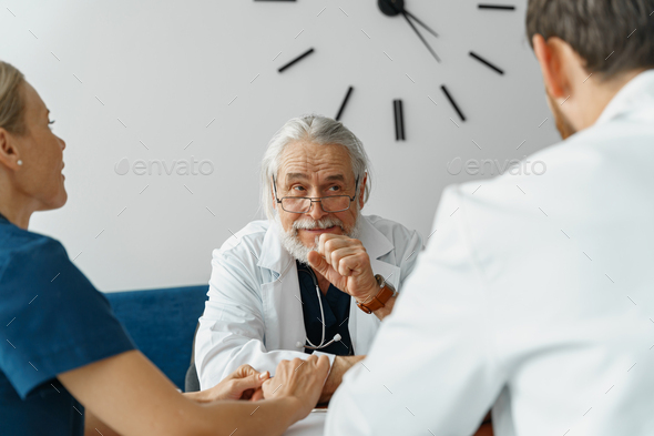 Group of doctors sitting at meeting table in conference room during ...
