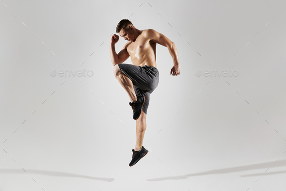 Handsome muscular man with perfect body jumping against white ...