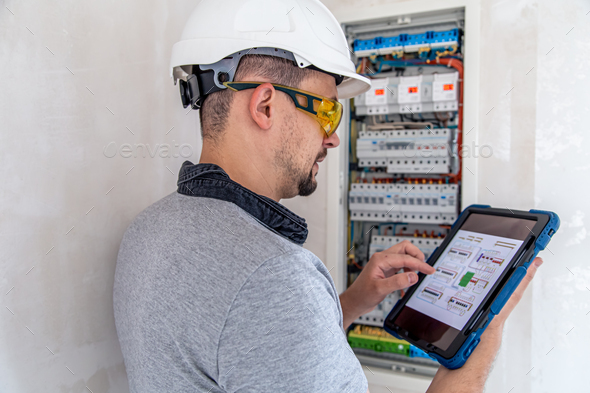 Electrical technician looking focused while working in a switchboard ...