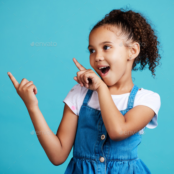 Shot of an adorable little girl pointing at something while standing ...