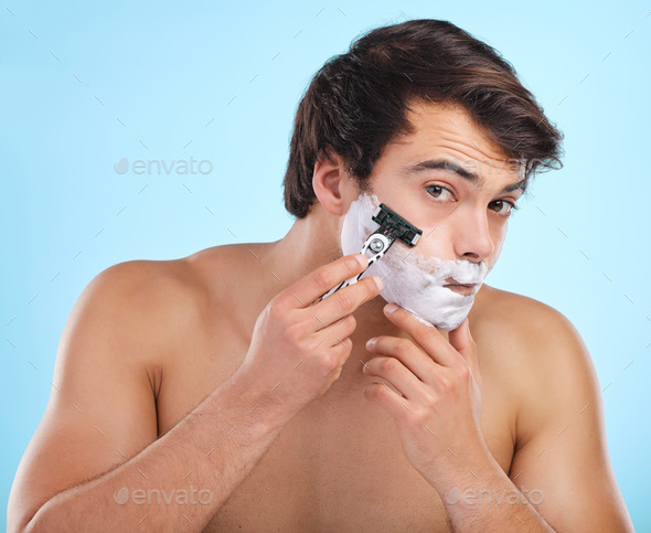 The best shave a man can get. Shot of a young man shaving his face against a studio background ...