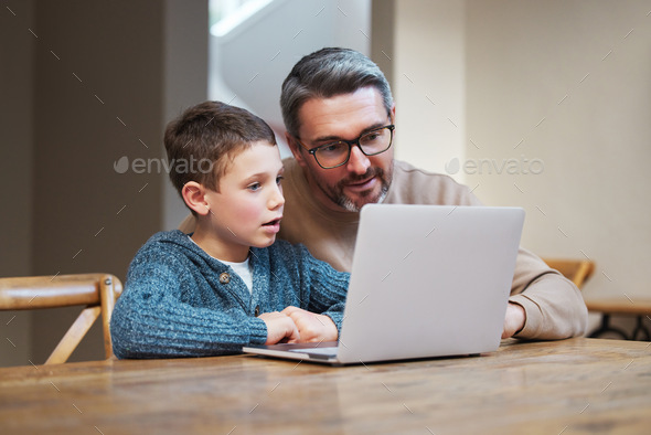 Shot of a father and son team using a laptop to complete school work ...
