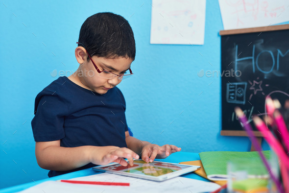 Shot of an adorable little boy using a digital tablet to complete a ...