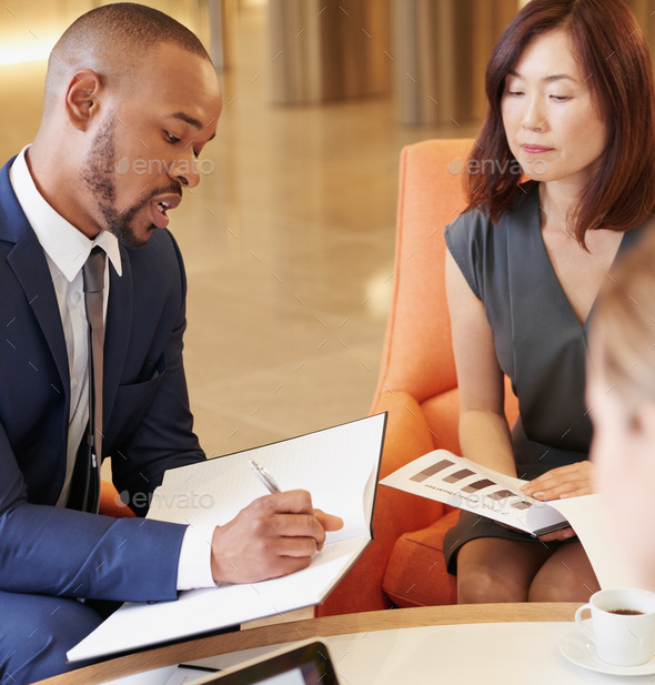Group of diverse business people with notepads having a meeting in ...
