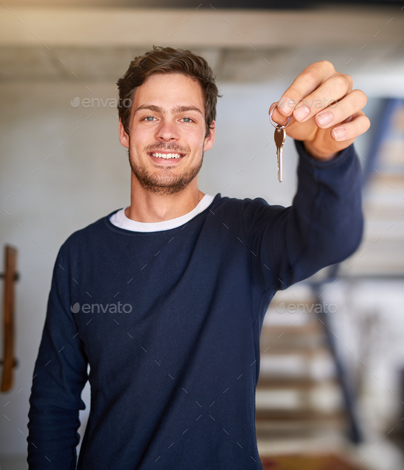 Hes one proud homeowner. Portrait of a happy young man holding up the ...