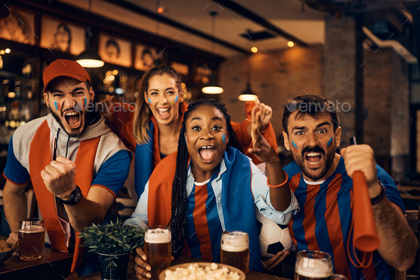 Passionate sports fans cheering while watching a game in pub. Stock ...