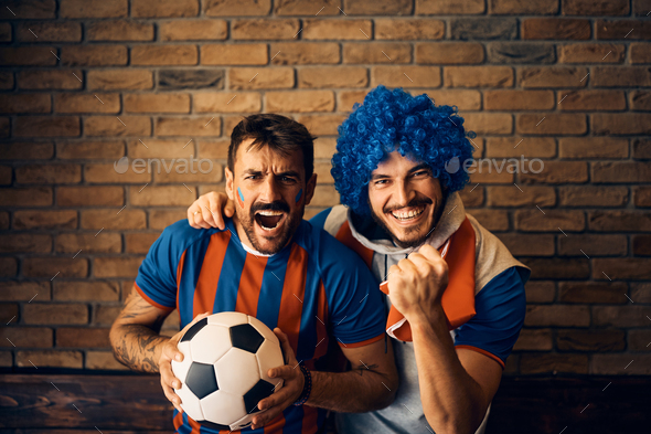 Passionate football fans cheering for their team while looking at ...