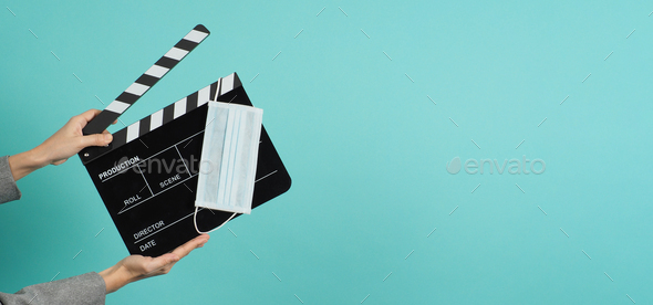 Hands with grey suit and hold black Clapper board on green mint ...