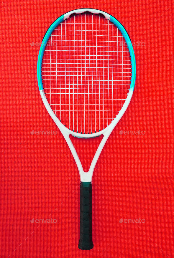 High angle shot of a single tennis racket placed on a red background ...