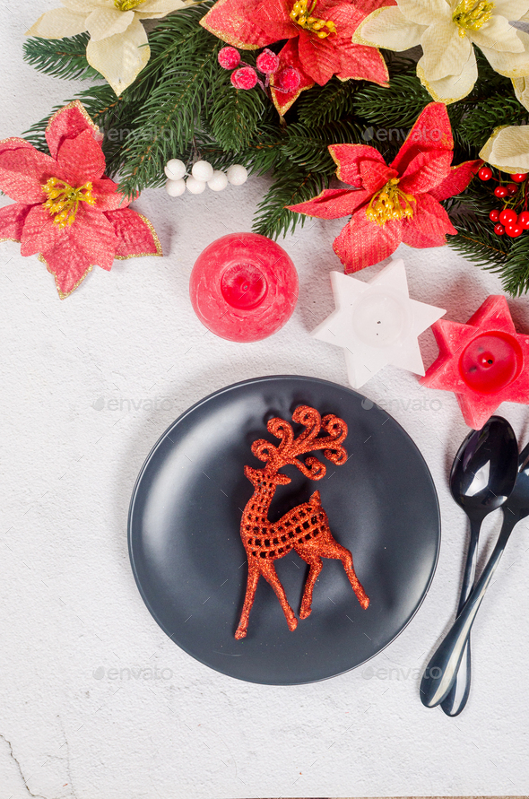 Christmas table setting with empty black plate and red decorations ...