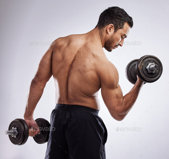 Make those biceps pop. Shot of a young man practicing his bicep curls ...