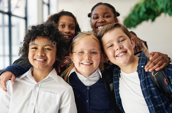 Shot of a diverse group of children standing together in the hallway at ...