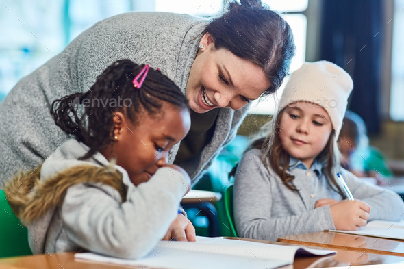 Cropped shot of elementary school girls getting help from their teacher ...
