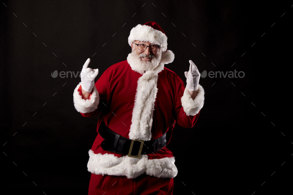 Santa Claus making a rocker gesture on black background Stock Photo by ...