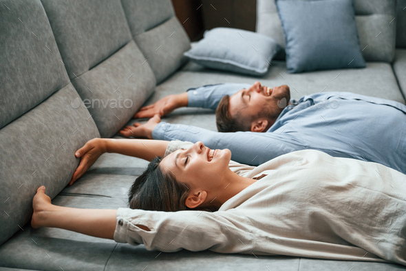 Laying down together. Couple choosing the sofa and bed in the store ...