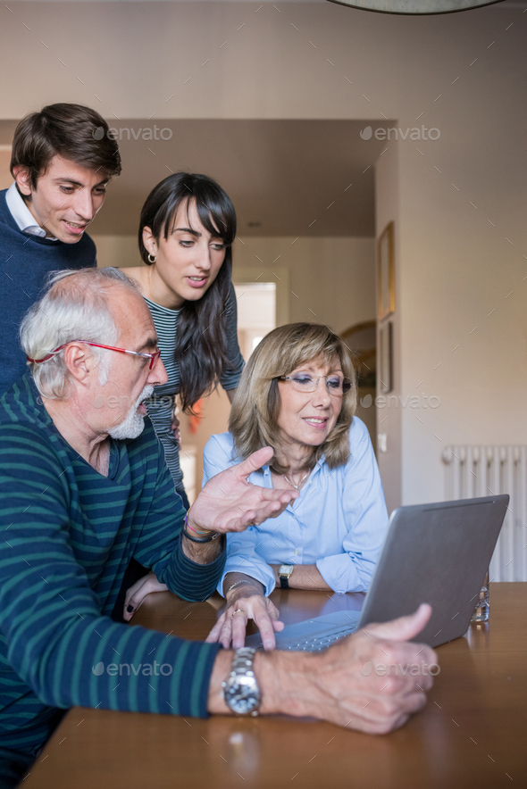 Son and daughter explaining parents use computer Stock Photo by peus80