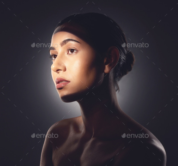 Studio shot of a beautiful young woman posing with light beam against ...