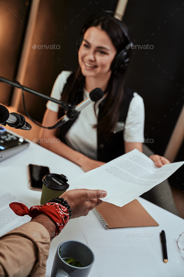 Close up of male hand holding, giving a script paper to female radio ...