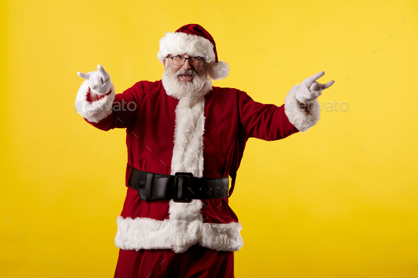 Santa Claus making a rocker gesture on yellow background Stock Photo by ...