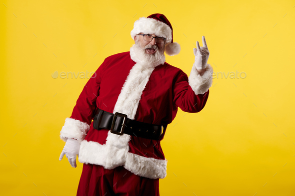 Santa Claus making a rocker gesture on yellow background Stock Photo by ...