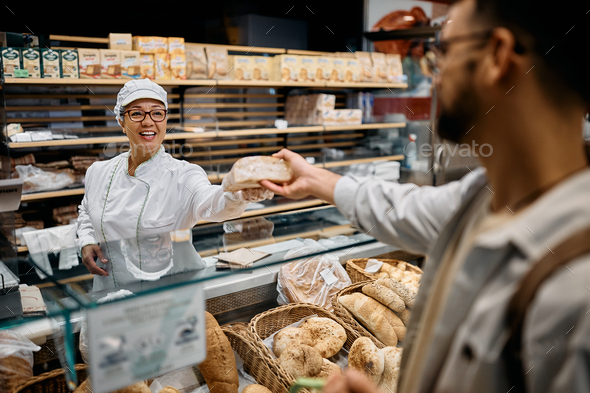 Happy supermarket baker serving male customer. Stock Photo by drazenphoto