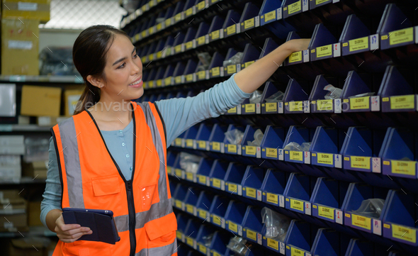Female warehouse worker Counting small parts stored in the blue storage ...