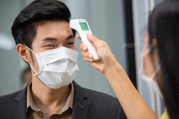 Asian employee woman using infrared thermometer check fever temperature ...