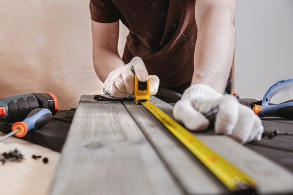 Professional carpenter makes accurate measurements with a yellow tape ...